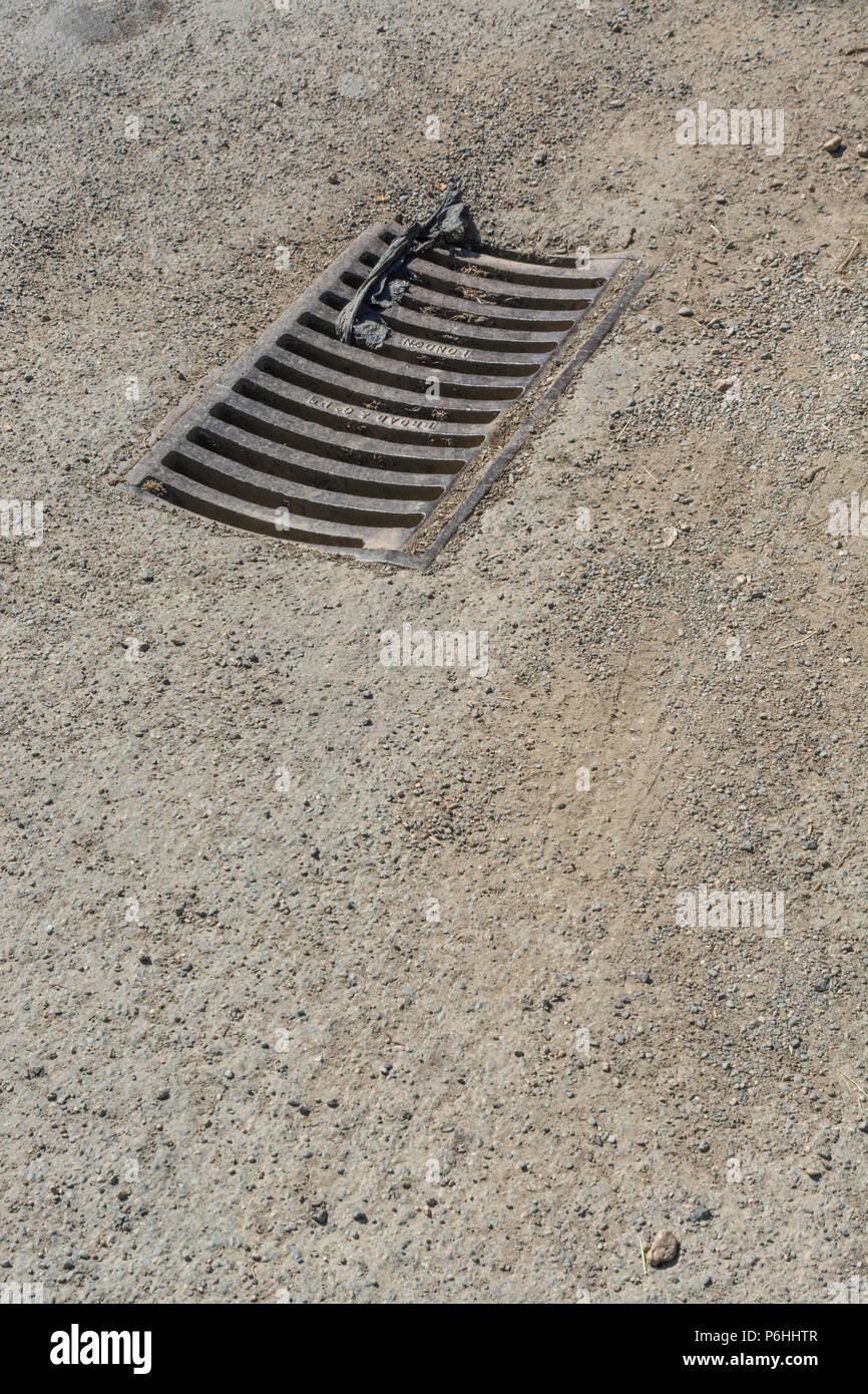 Drainage grille on a country lane. Metaphor 'down the drain' Stock ...