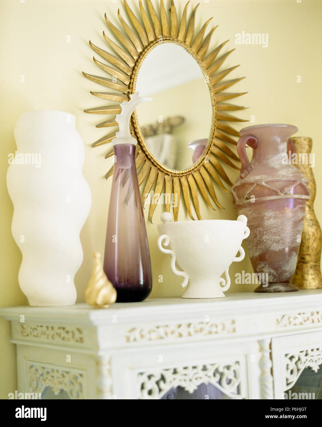 Gilt sunburst mirror above ceramic and glass vases on fretwork console ...