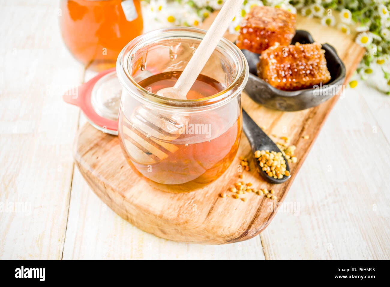 Organic floral honey, in jars, with pollen and honey combs, on a white ...