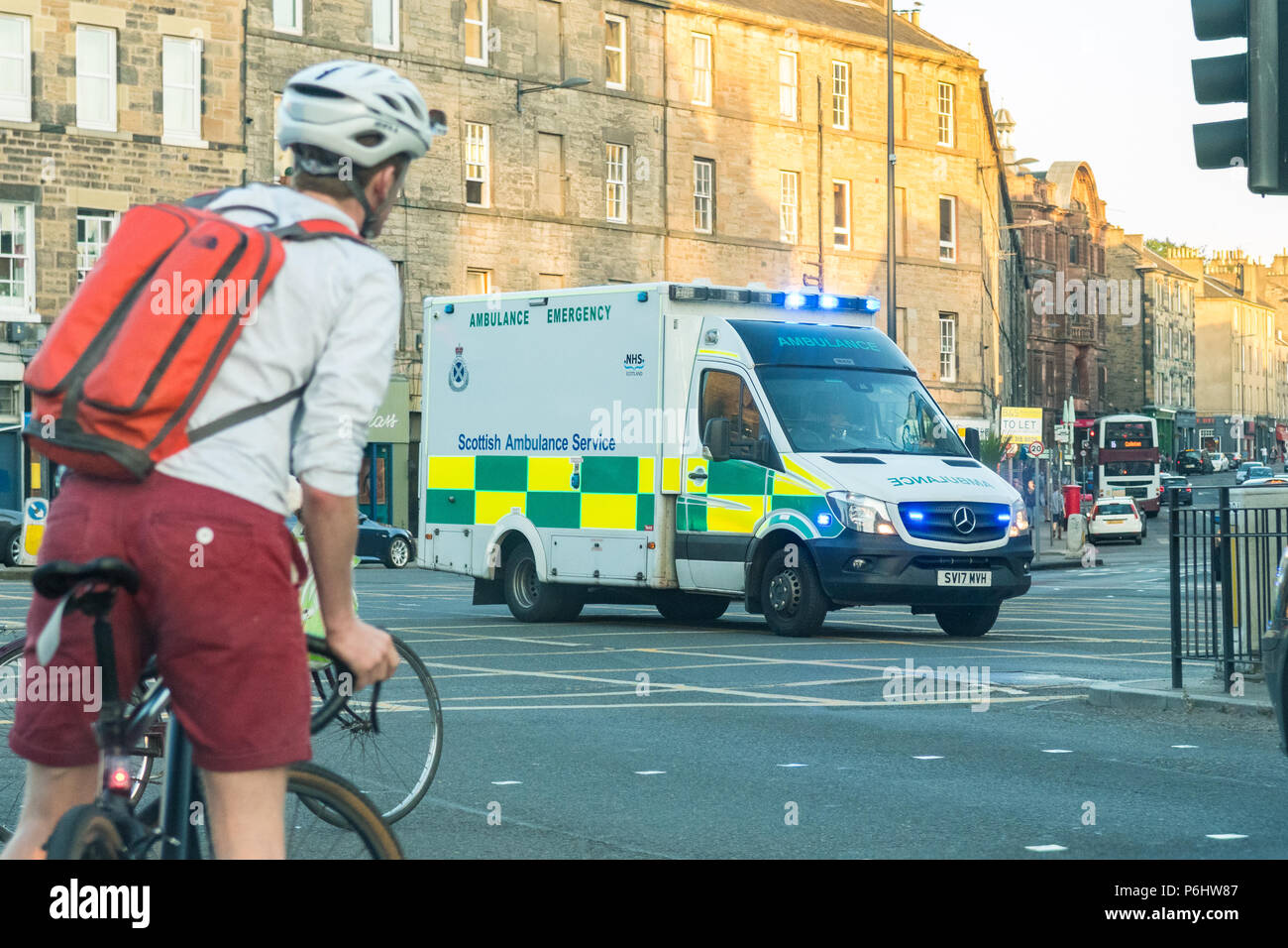Ambulance with blue flashing lights driving through Edinburgh city ...