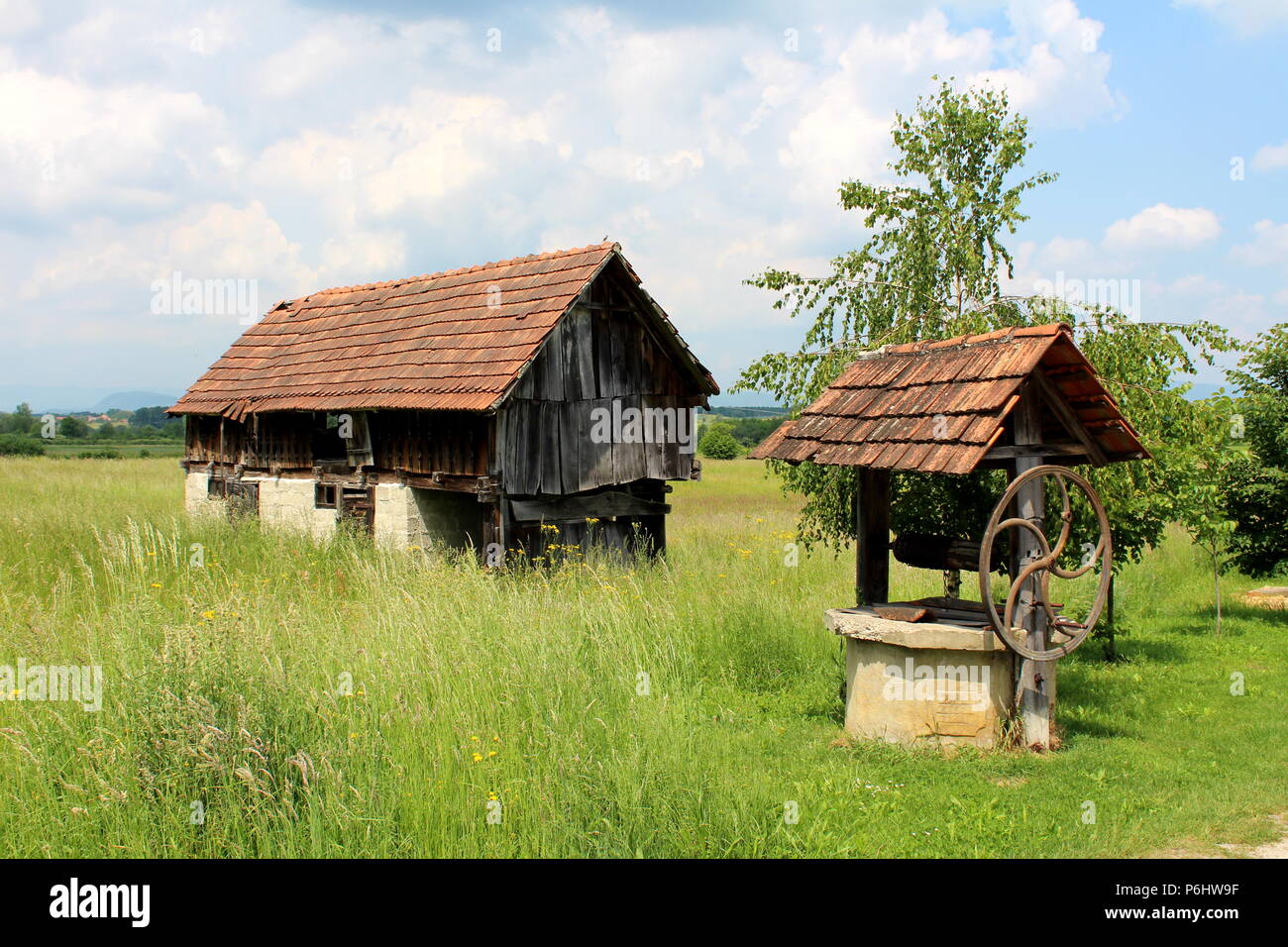 Dilapidated abandoned old wooden well and barn with brick foundation made of old wooden boards ...
