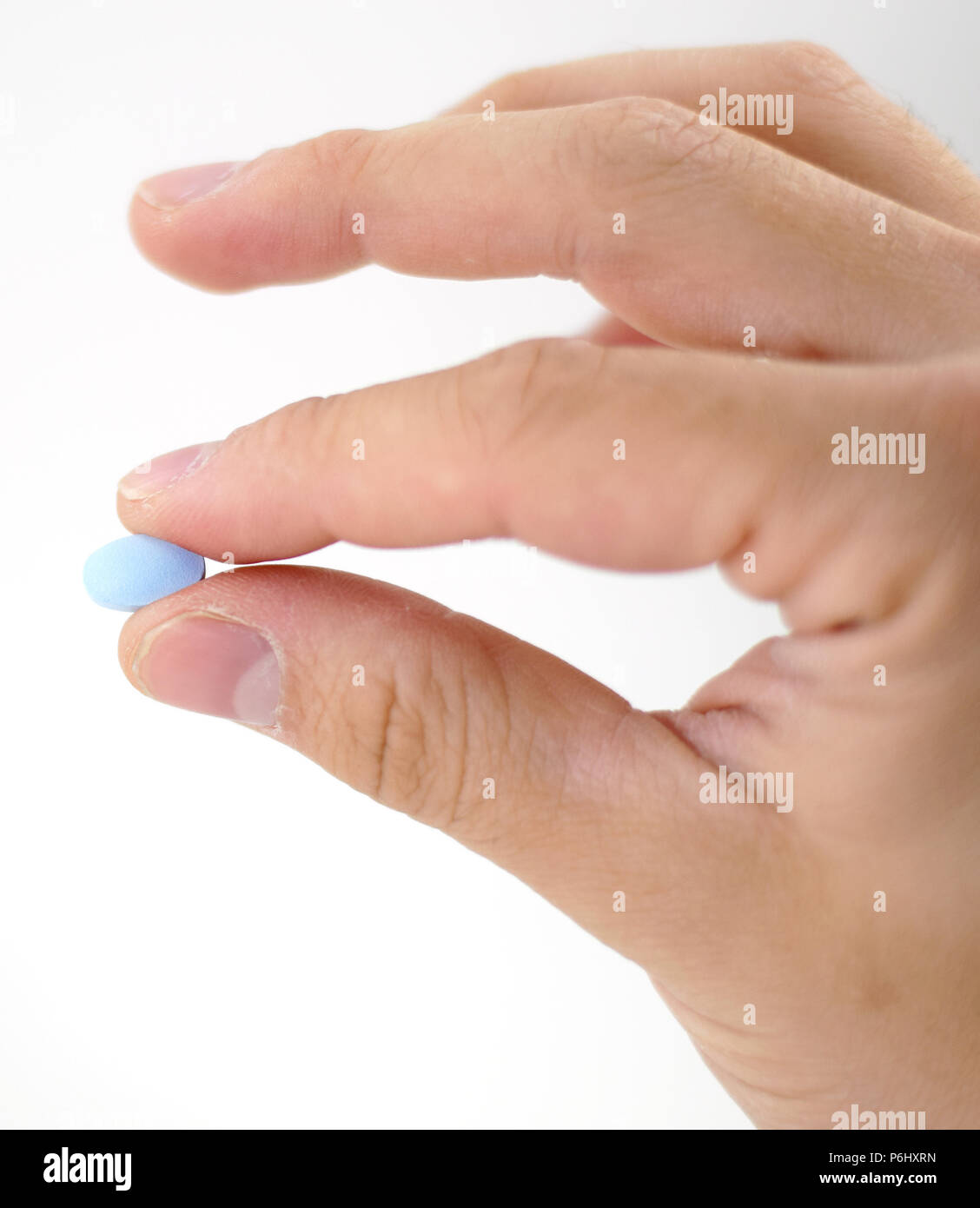 Male hand holding blue pill between fingers - isolated Stock Photo - Alamy