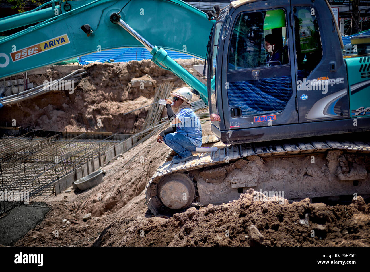 Thailand building site with man sitting on the wheel track of a ...