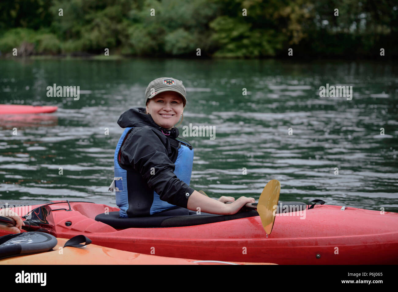 Young blonde girl swims on a sports boat kayak on a beautiful river ...