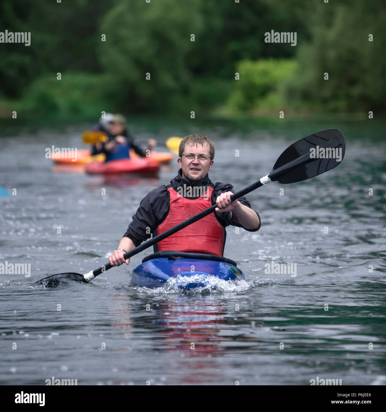 middle-aged man actively manages a sports boat with a kayak on a wide ...