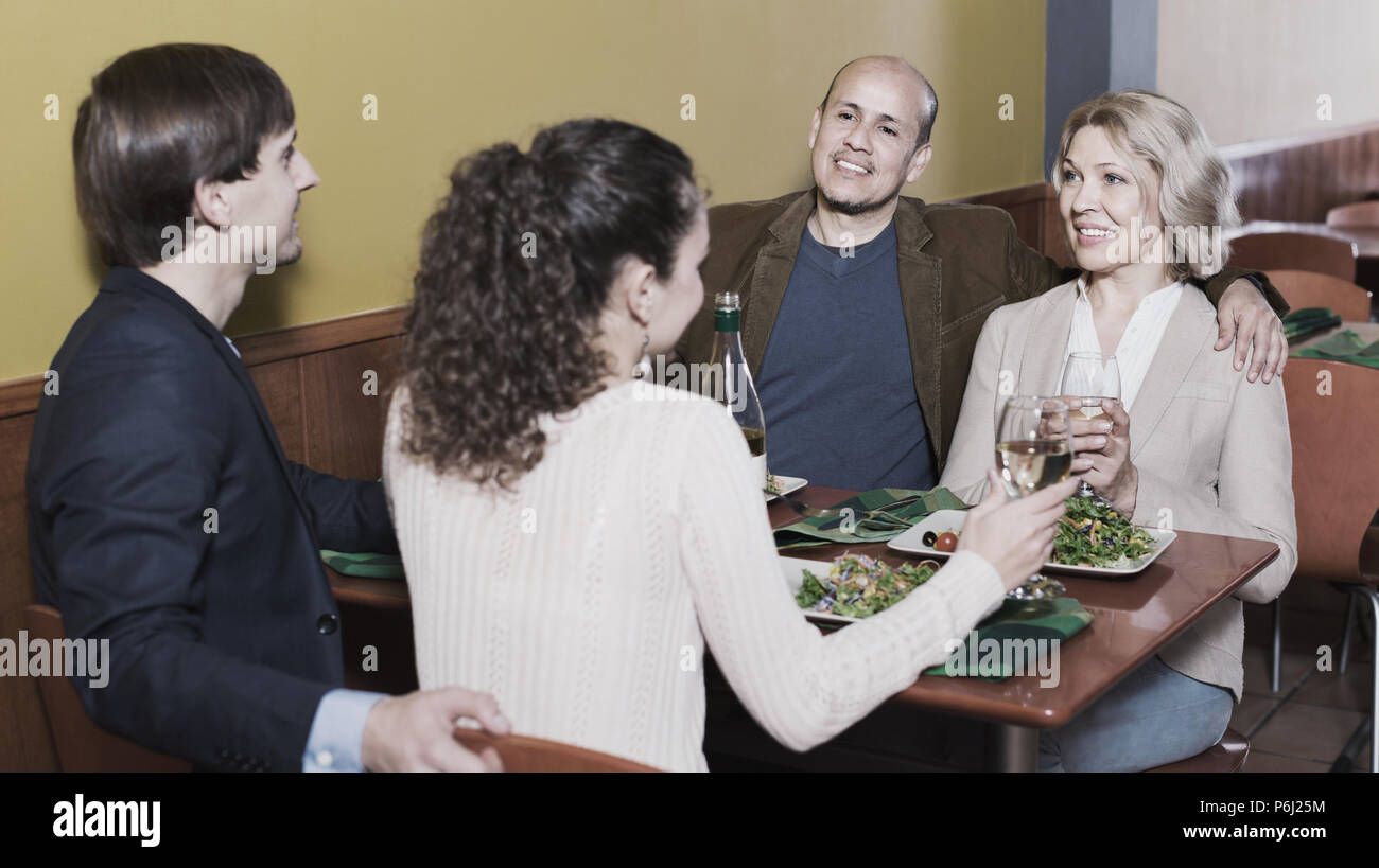 Pleasant cheerful middle class people enjoying food and wine in cafe ...
