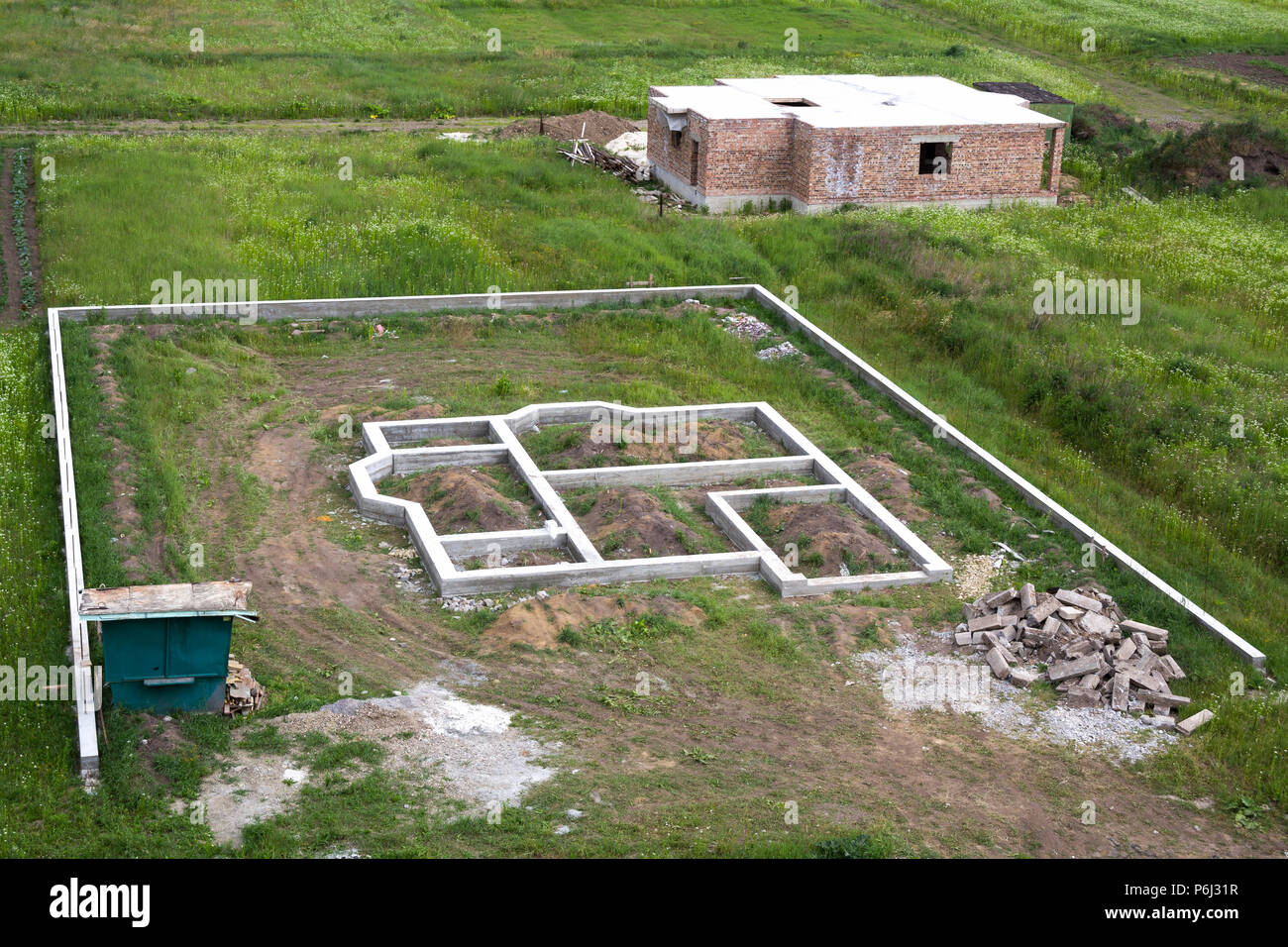 Building site in green field. Trenches dug in ground and filled with ...