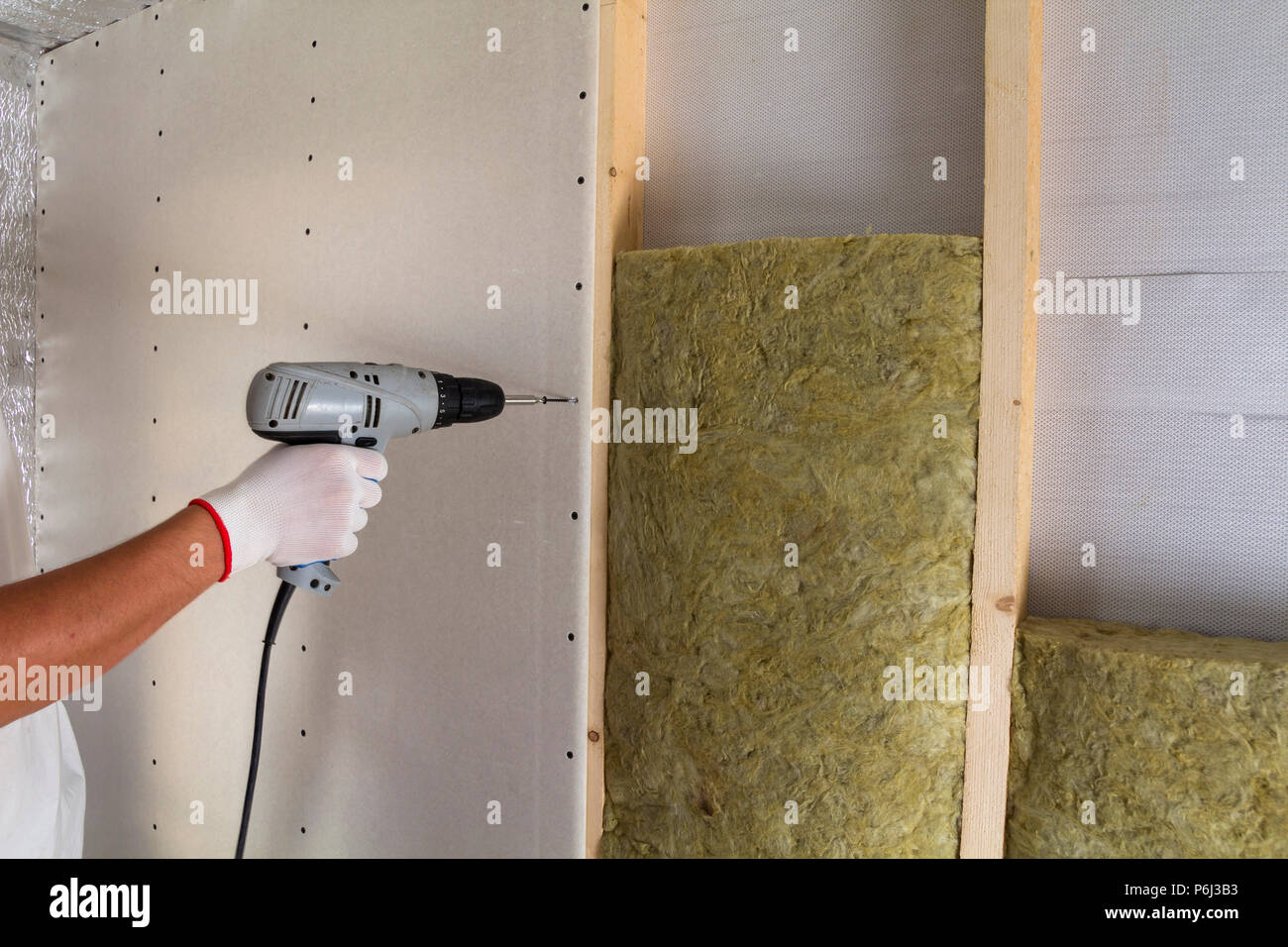 Close-up of worker hand with electric screwdriver fastening drywall to ... Close-up of worker hand with electric screwdriver fastening drywall to ...