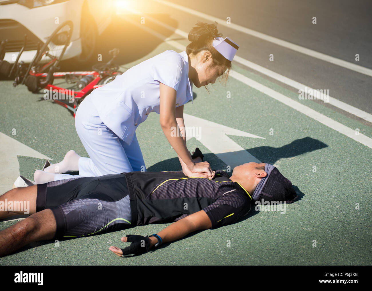 Female nurse helping emergency CPR to asia cyclist injured on the ...