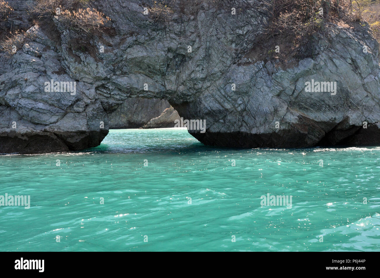 A View of a Cliff through a hole in a Cliff surrounded by a Teal Blue ...
