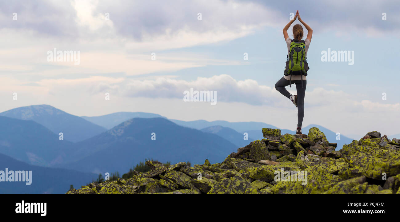 Back view of young slim tourist girl with backpack standing on one leg ...
