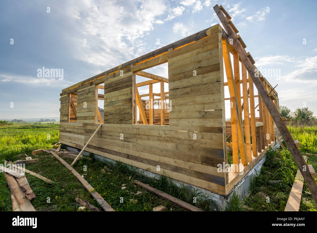 Unfinished ecological house under construction in green field on blue ...