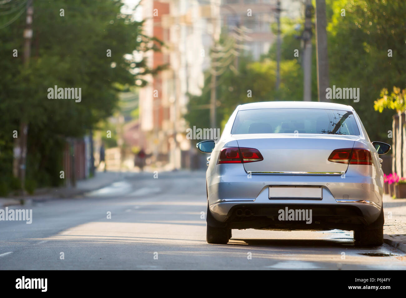 Close-up back view of new shiny expensive silver car moving along city ...