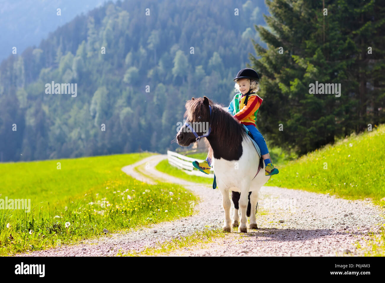 Kids riding pony in the Alps mountains. Family spring vacation on horse ...