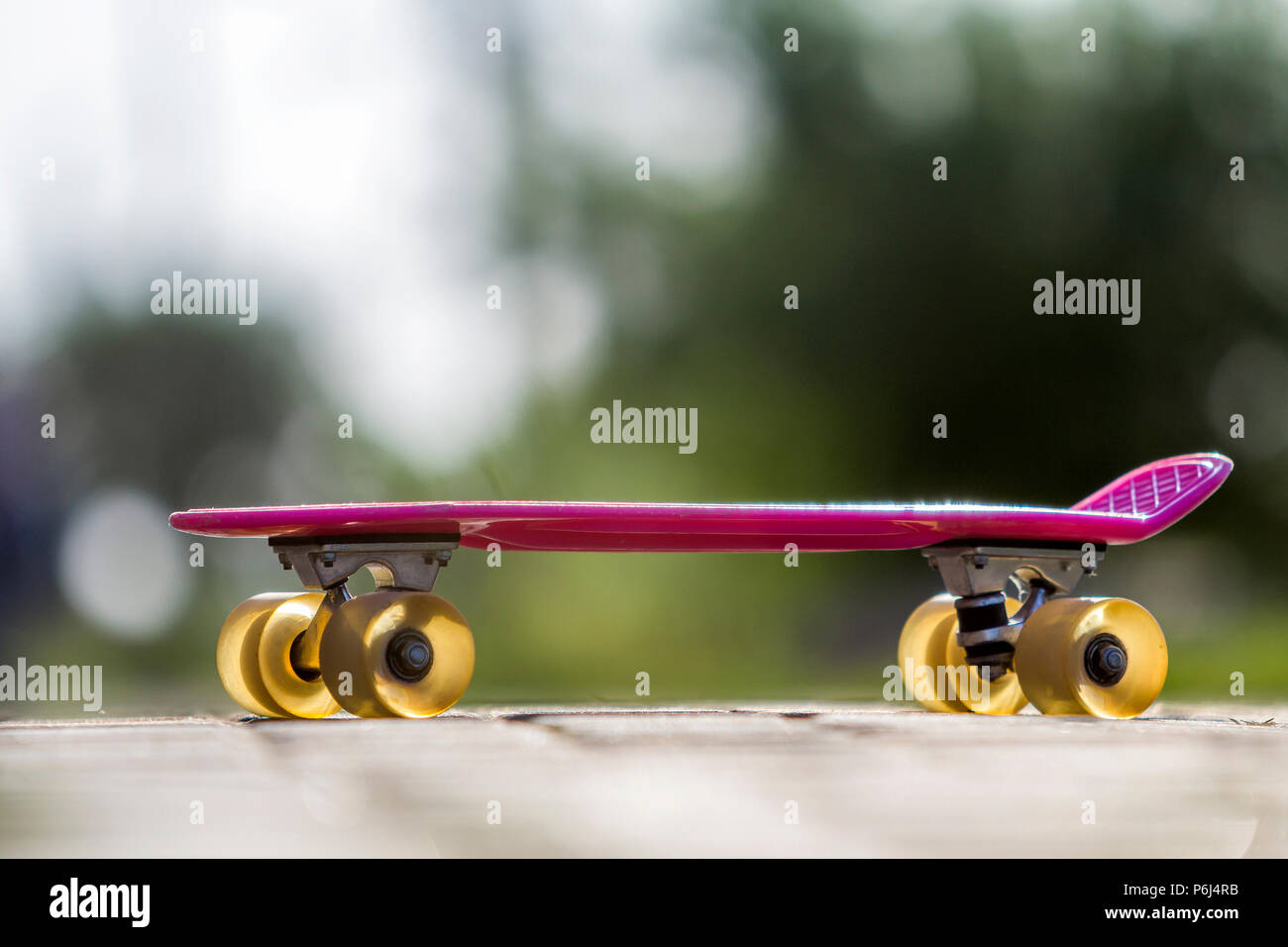 Close-up of child plastic pink skateboard isolated on pavement against ...