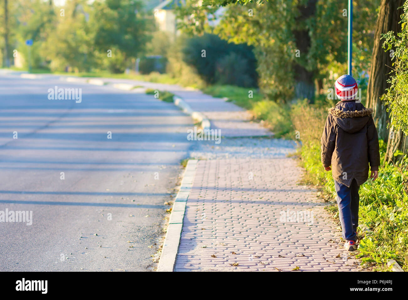 Child boy walking alone on a sidewalk Stock Photo - Alamy