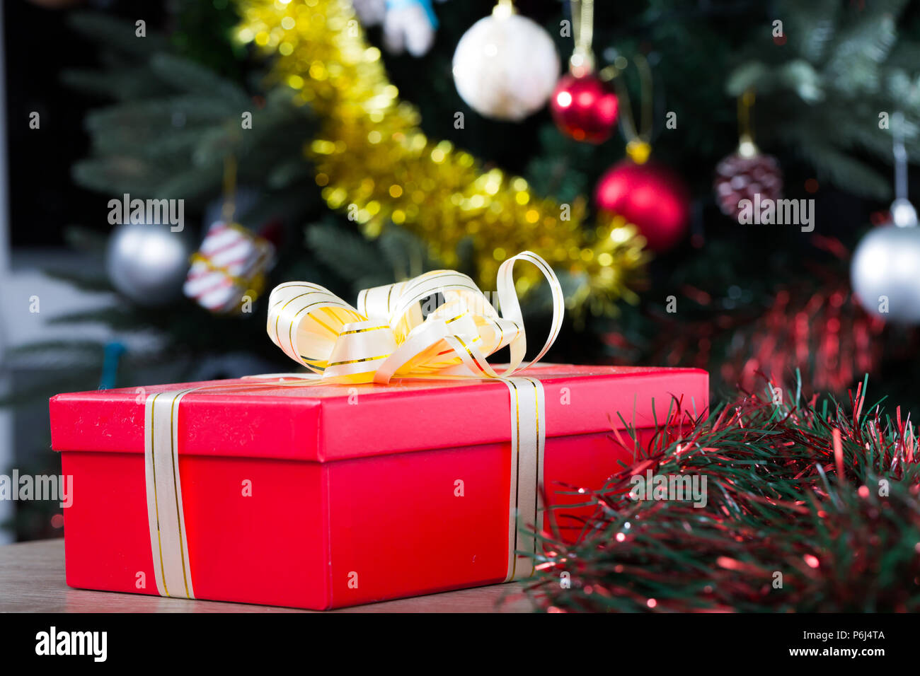 Red gift box with gold ribbon on blurry background with decorated ...