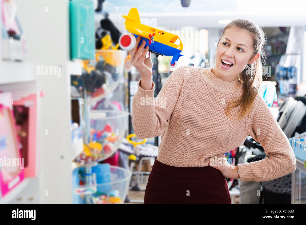 smiling young consumer with children's plastic toys in the kids store ...