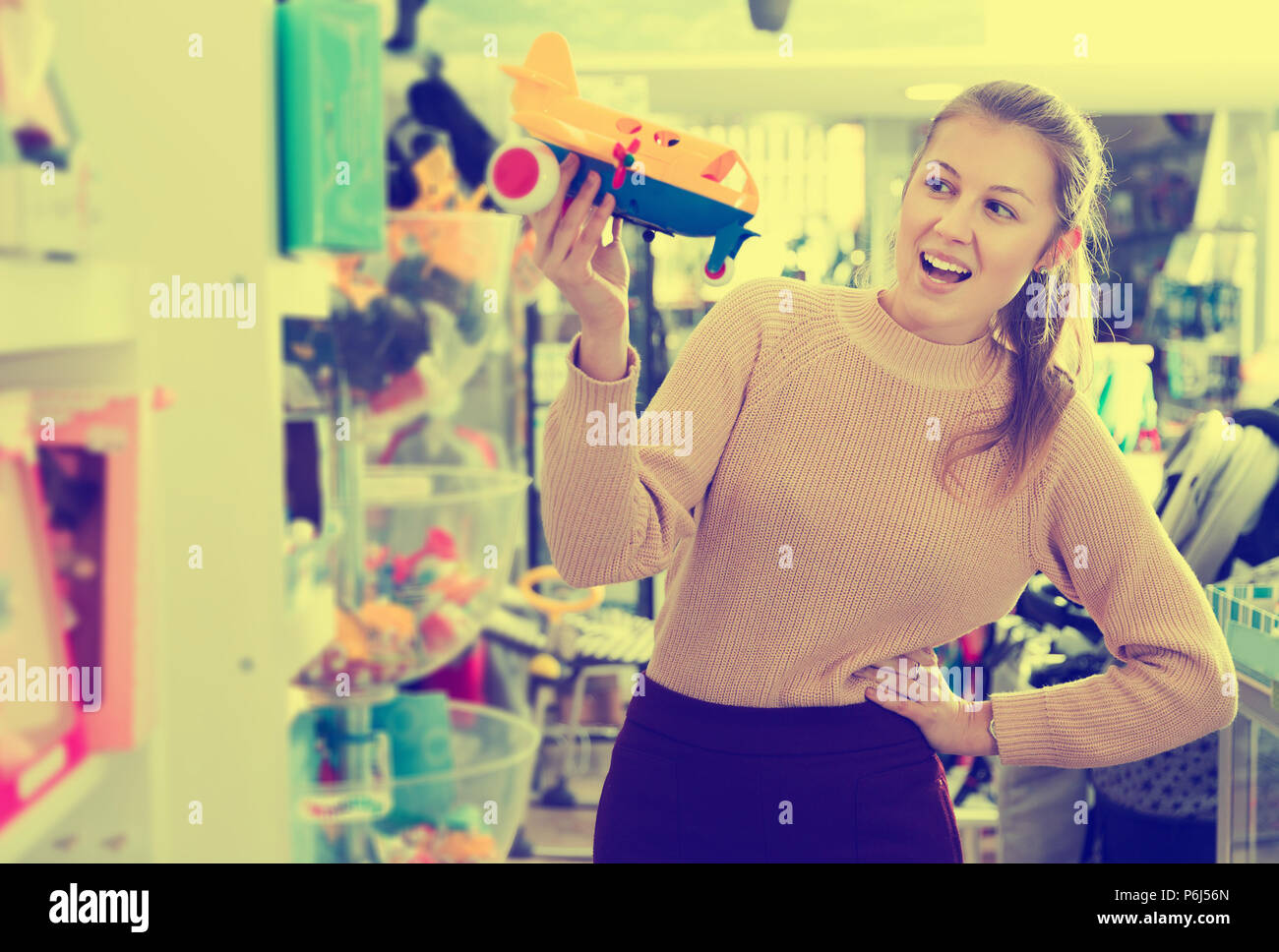 smiling young consumer with children's plastic toys in the kids store ...