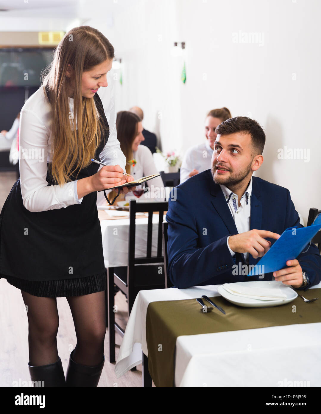 Welcoming female waiter is taking order from businessman in restaurante ...