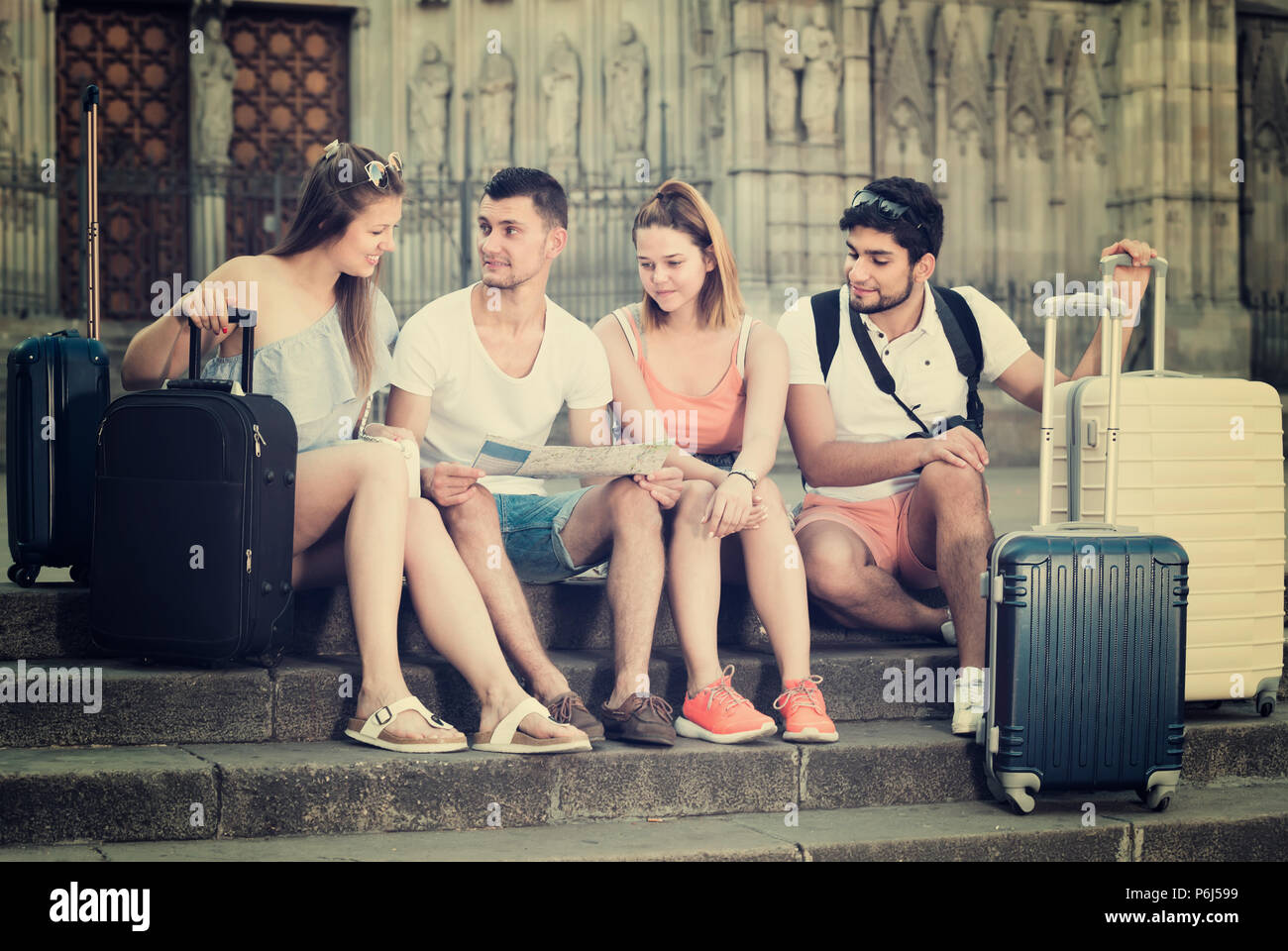 four attentive traveling young people searching for direction using ...
