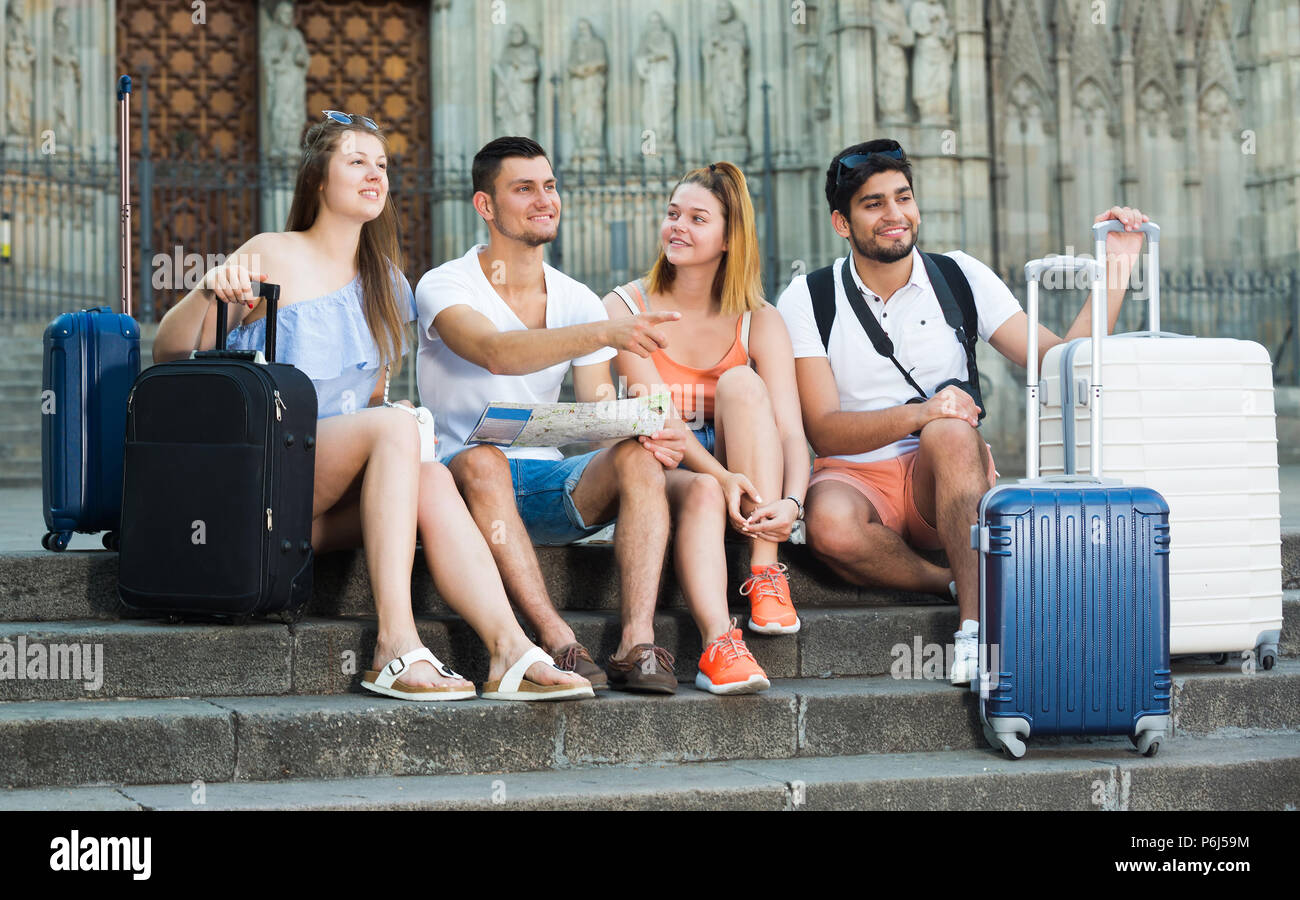 Group of young traveling people searching for direction using paper map ...