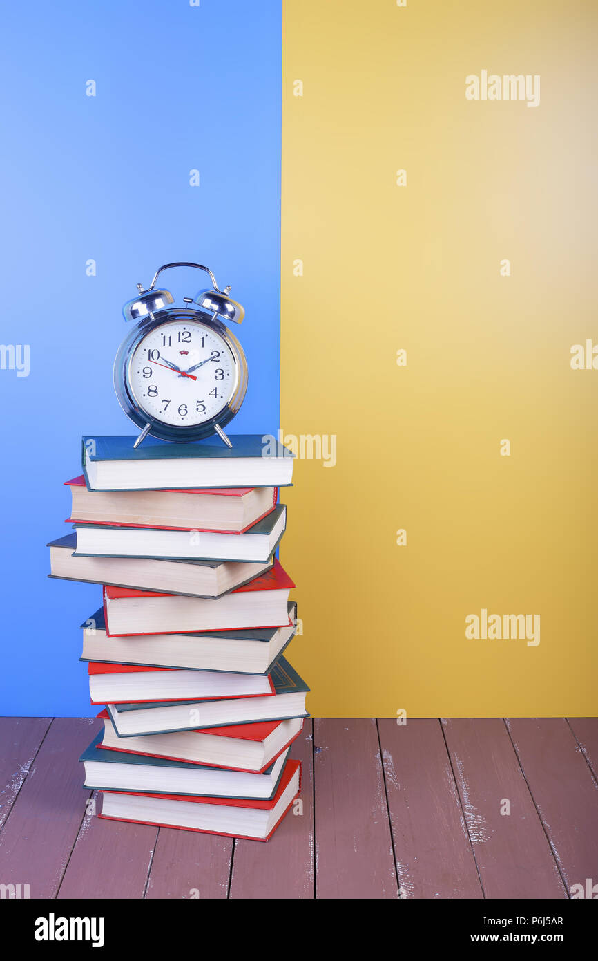 Science and education - alarm clock and high pile group of red books on ...