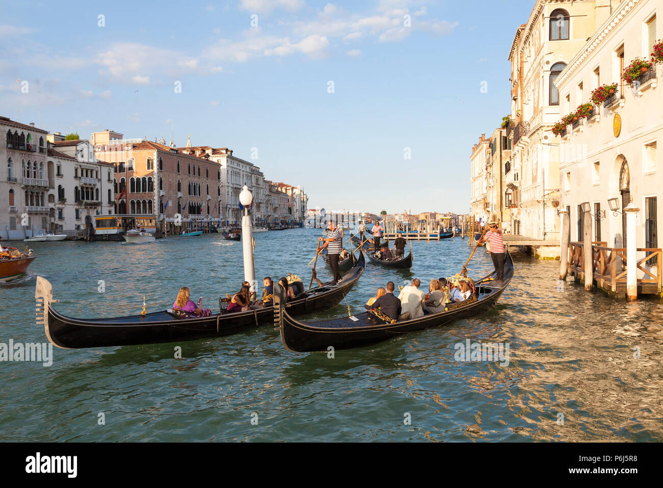 Tourists enjoying romantic gondola rides at sunset on the Grand Canal ...