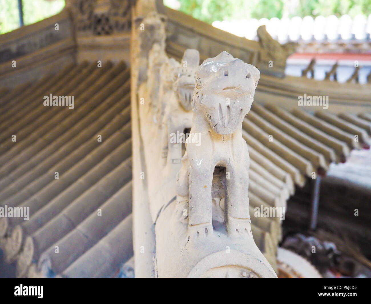 Faded blue clay mythical roof figurines and eaves ready to be renovated ...