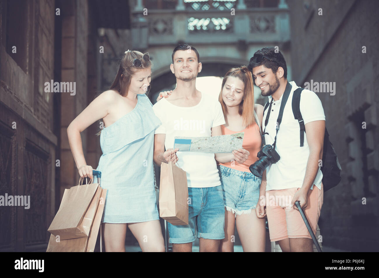 Group of young traveling people searching for direction using paper map ...