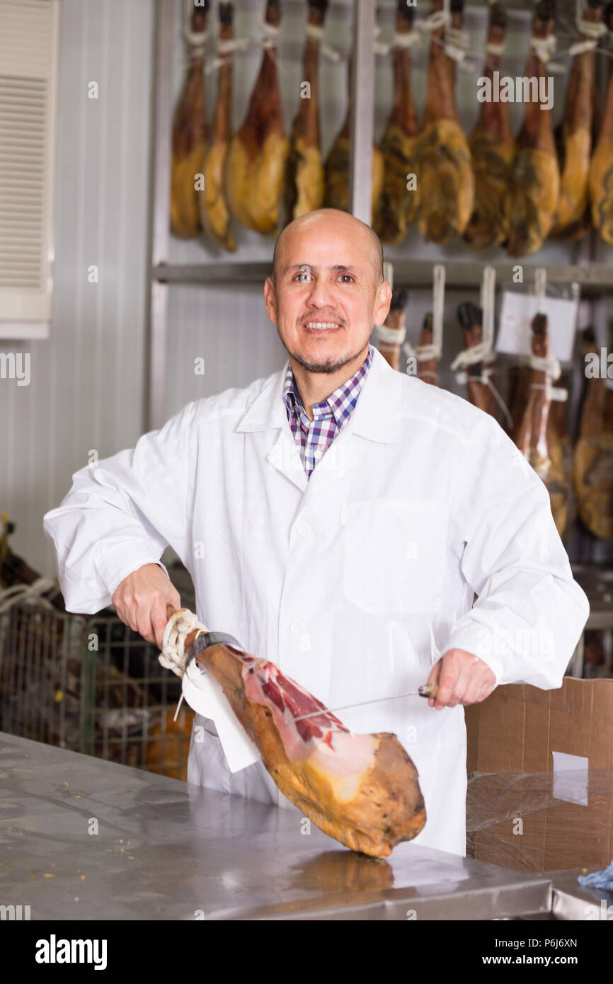 Salesman cutting jamon on slices inin delicatessen section of market ...