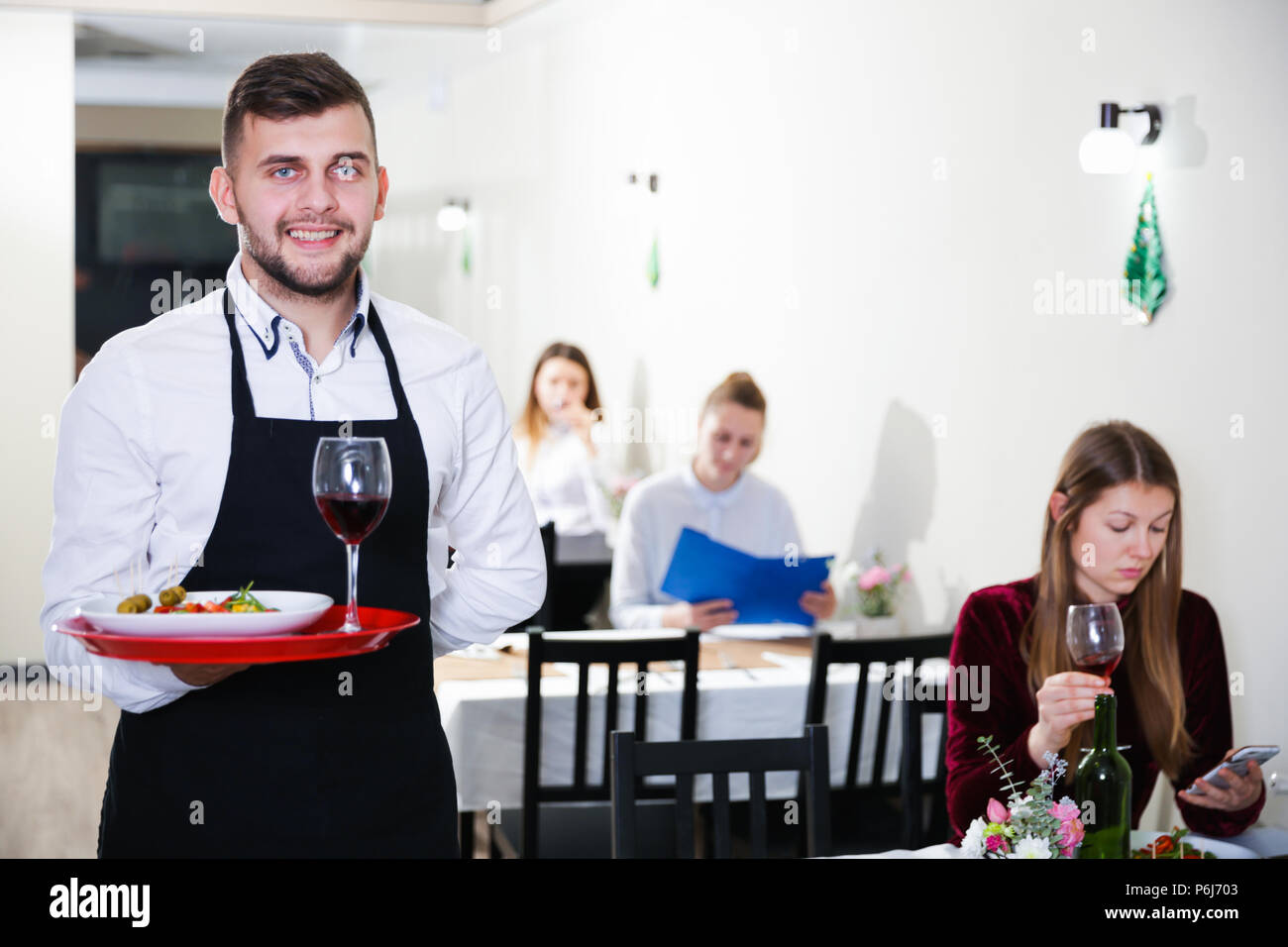 Portrait of welcoming waiter who is standing in restaurante indoor ...