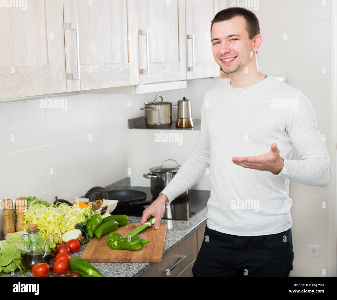 Portrait of male cooking with vegetables on cutting board at the ...