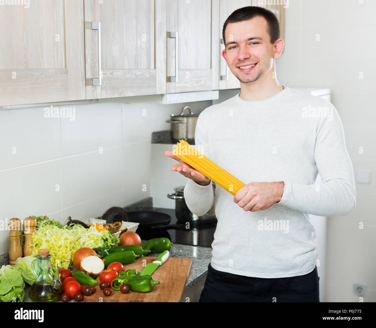 Happy handsome man cooks lunch with spaghetti in a home interior Stock ...