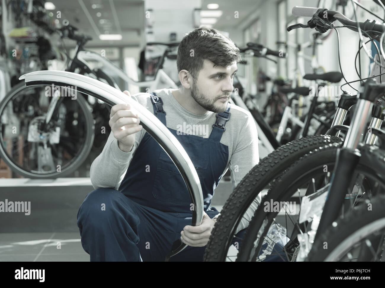 Cheerful professional man holding cycle frame in bicycle shop Stock ...