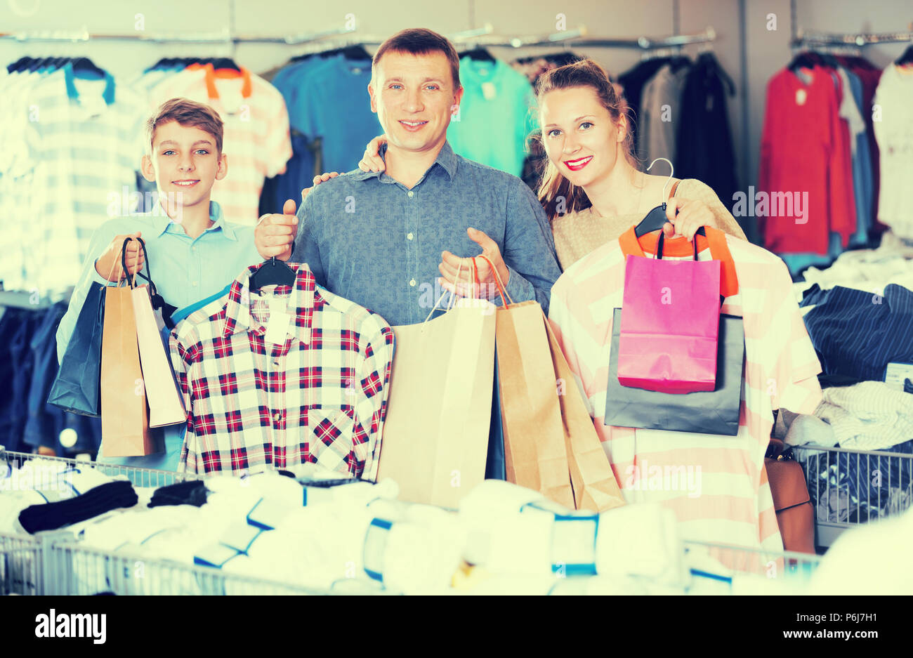 Family couple with teen showing shopping bags with purchases in clothes ...