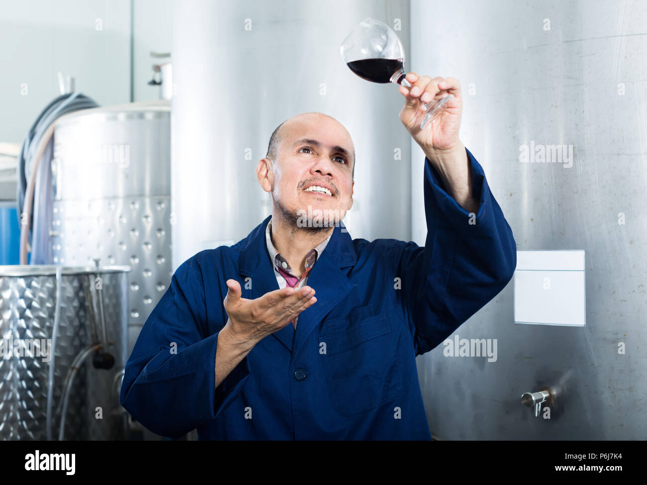 happy mature man winery worker looking at glass of red wine on ...