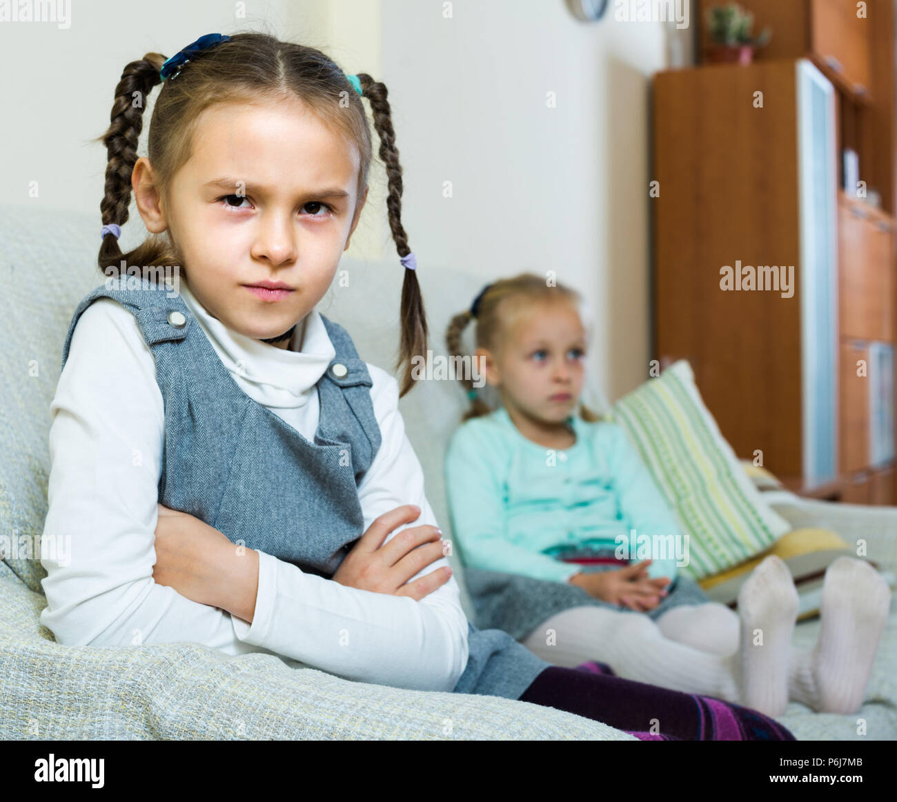 Offended little girl sitting apart of younger sister after conflict at ...