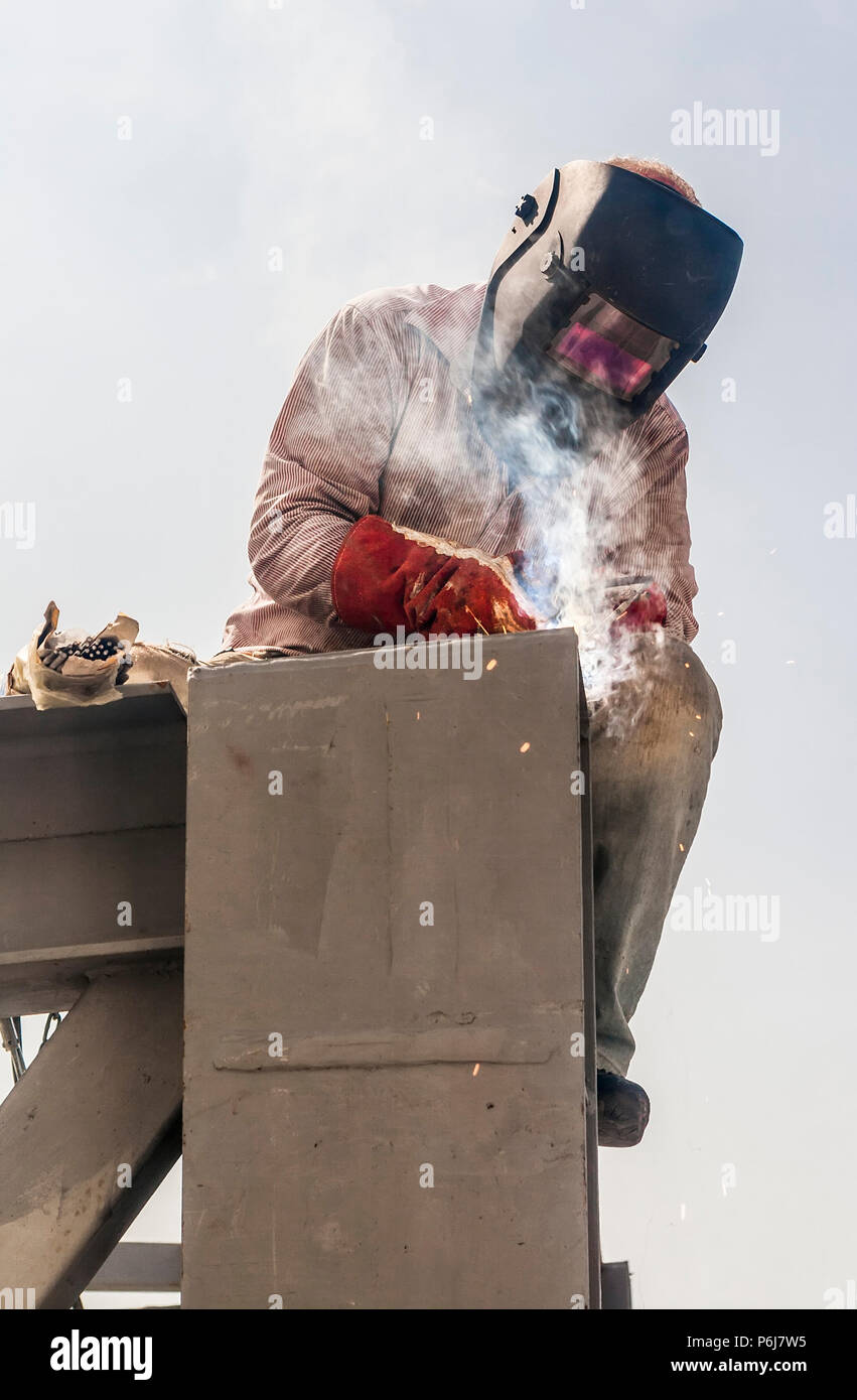 Welder at work, sitting on a metal structure Stock Photo - Alamy