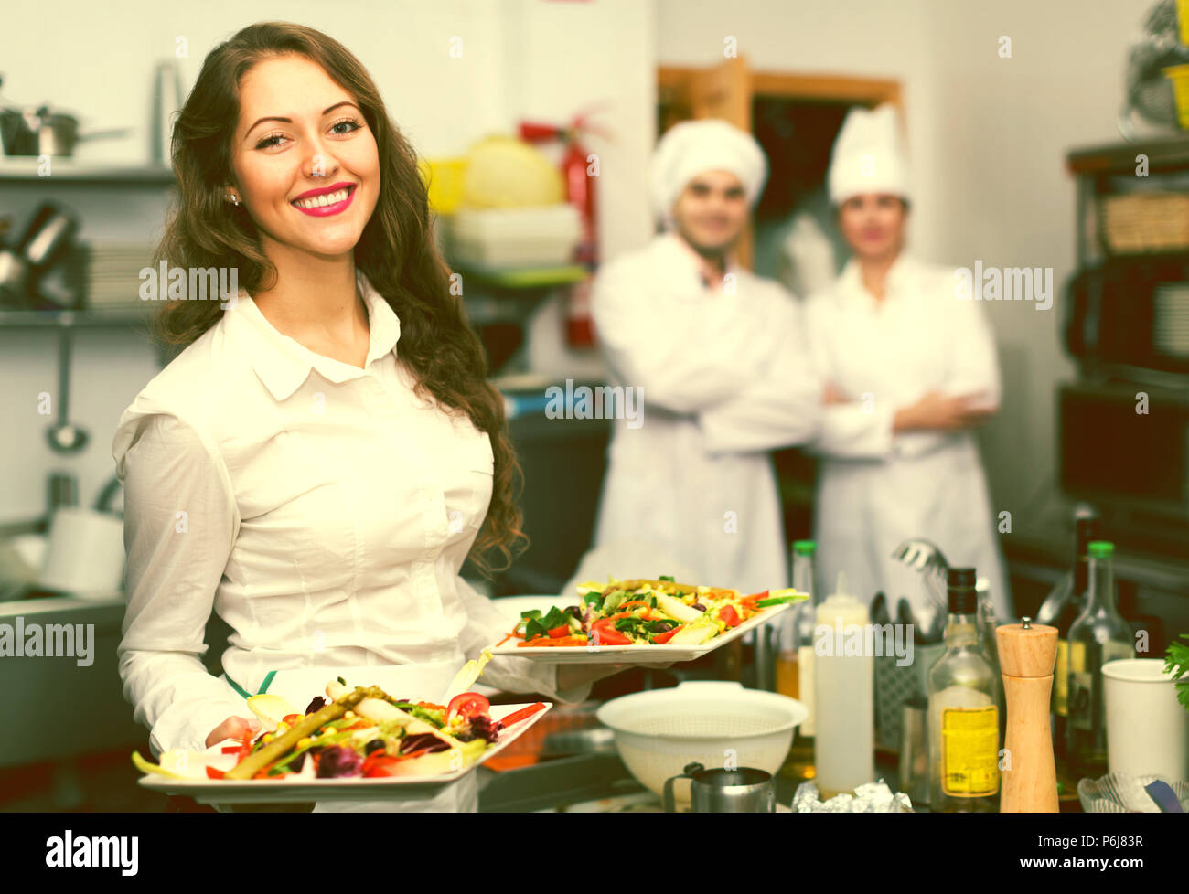 Team of chefs and young beautiful waiter in restaurant kitchen Stock ...