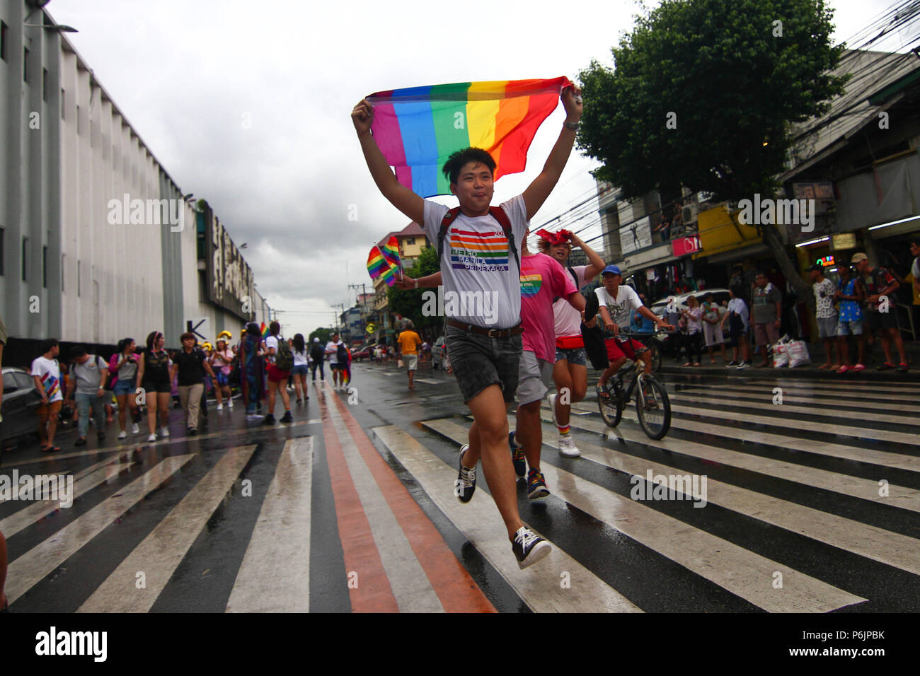 A Pride march participant runs while holding a gay rainbow flag during ...