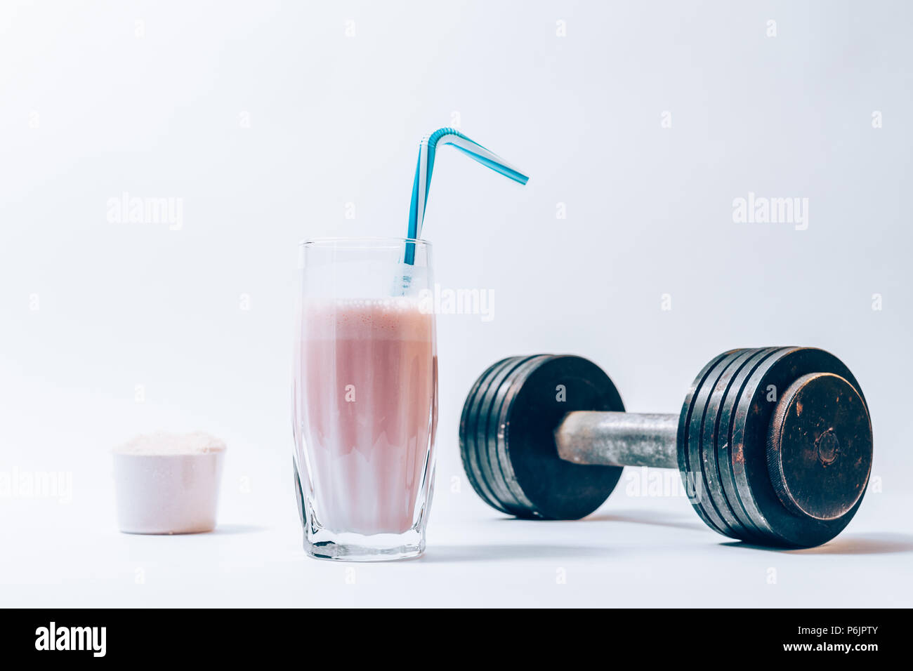 Glass of protein shake with a straw next to a portion of dry powder in ...