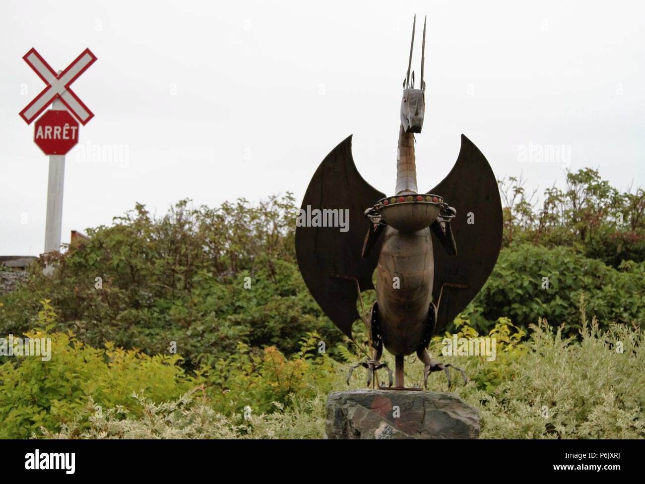 Metal bird sculpture with a stop and railway sign in background Stock ...