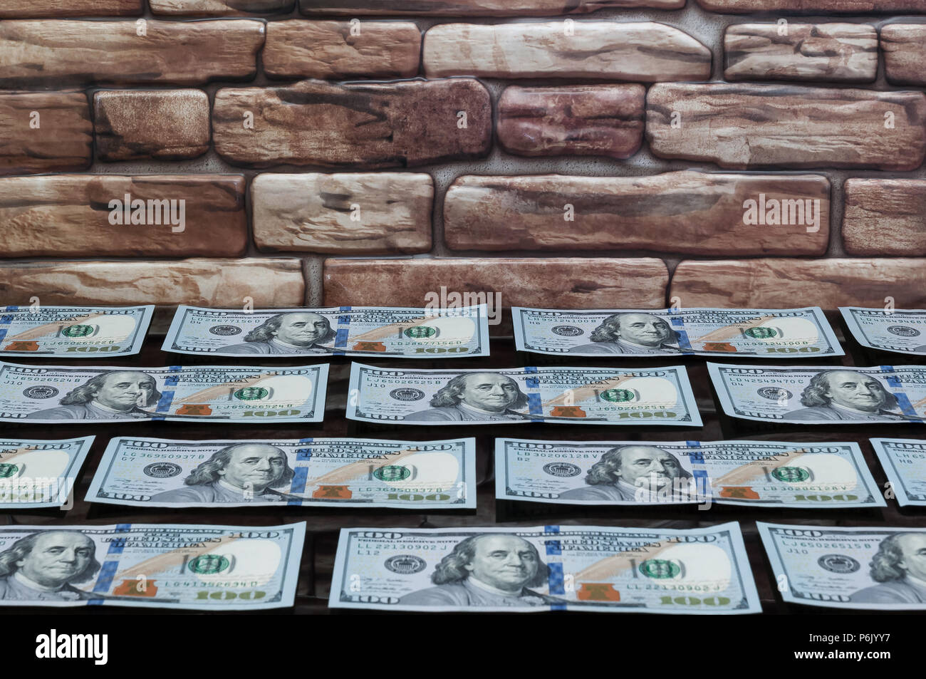 bills of one hundred dollars on a table of black glass near a brick ...