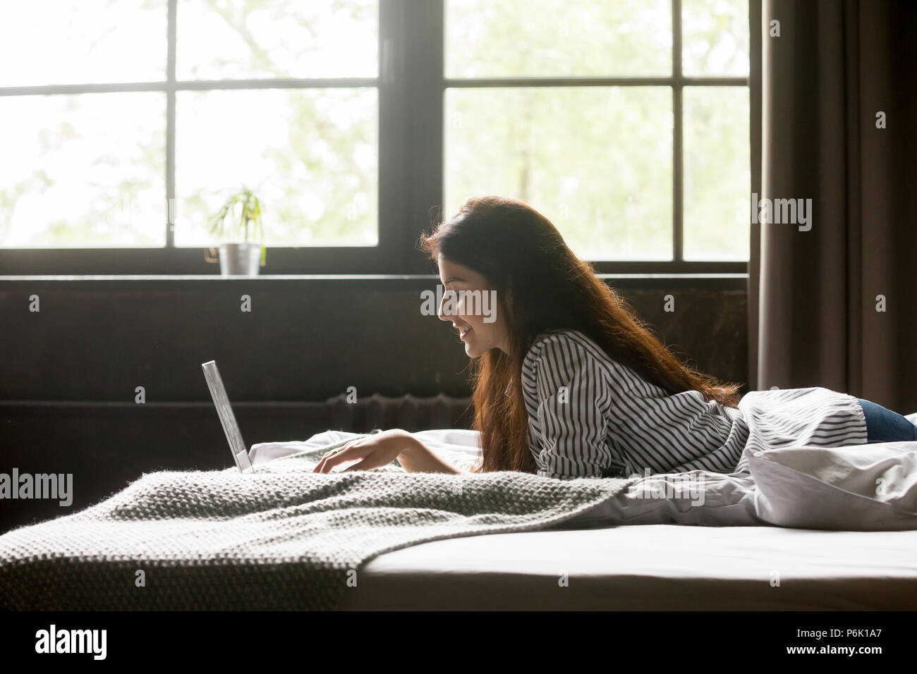 Happy girl smiling while texting to boyfriend at laptop Stock Photo - Alamy