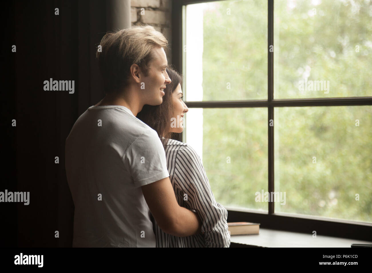 Thoughtful romantic couple dreaming looking in window Stock Photo - Alamy