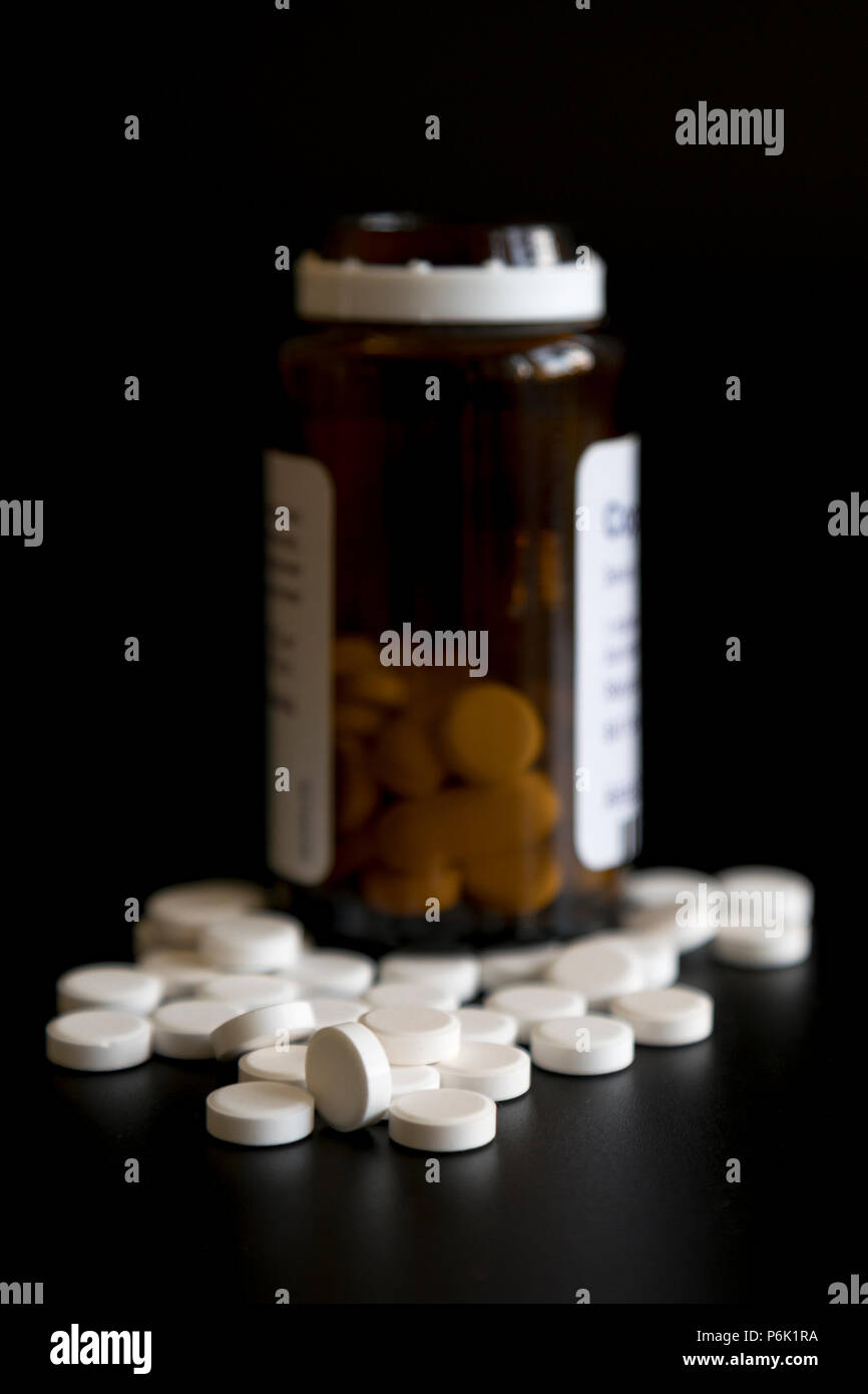 Tablets on a black background from a jar. jar with pills on a black ...