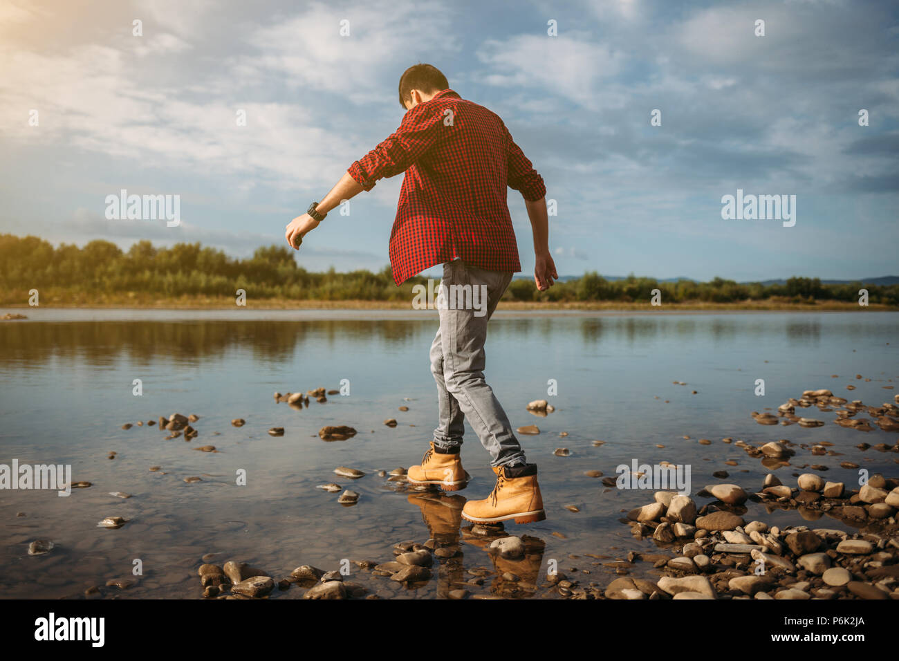 Hiker man crossing the river to reach the other side Stock Photo - Alamy