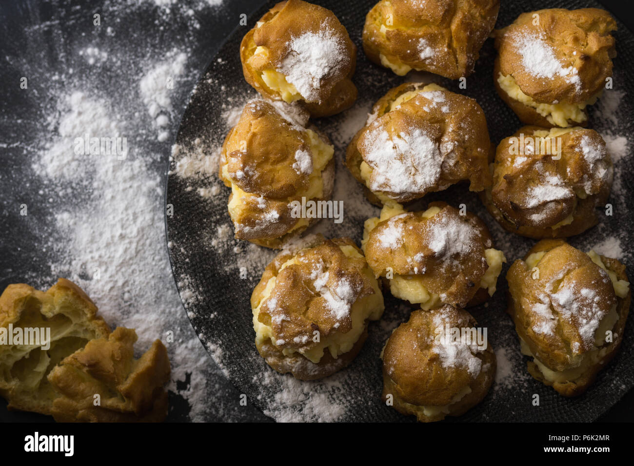 Cream puffs on dark background covered with sugar, top view Stock Photo ...