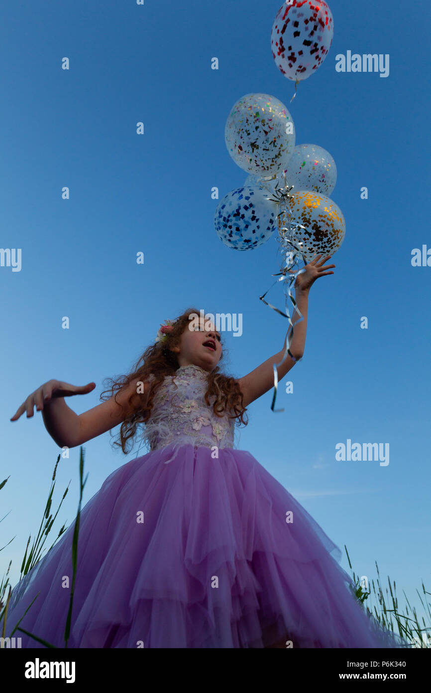 Little girl on a walk in a field with balloons, summer evening Stock ...